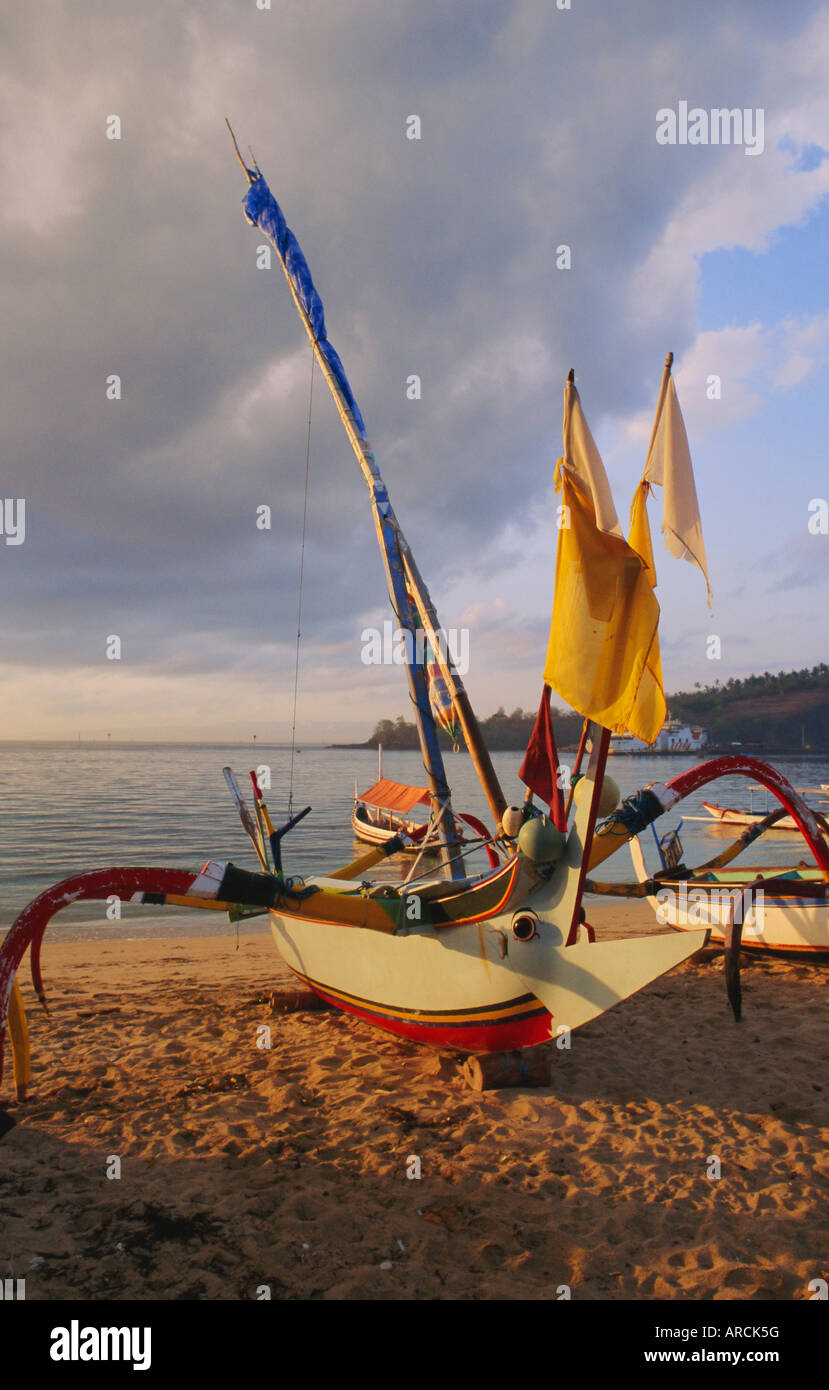 Traditional outrigger boats drawn up on the beach in the early evening ...