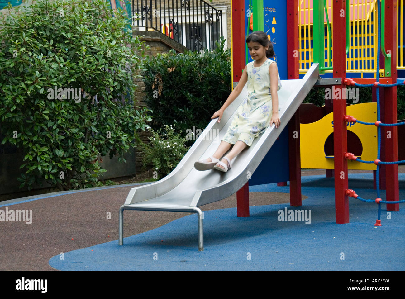 Girl sliding down a slide in a playground Stock Photo - Alamy
