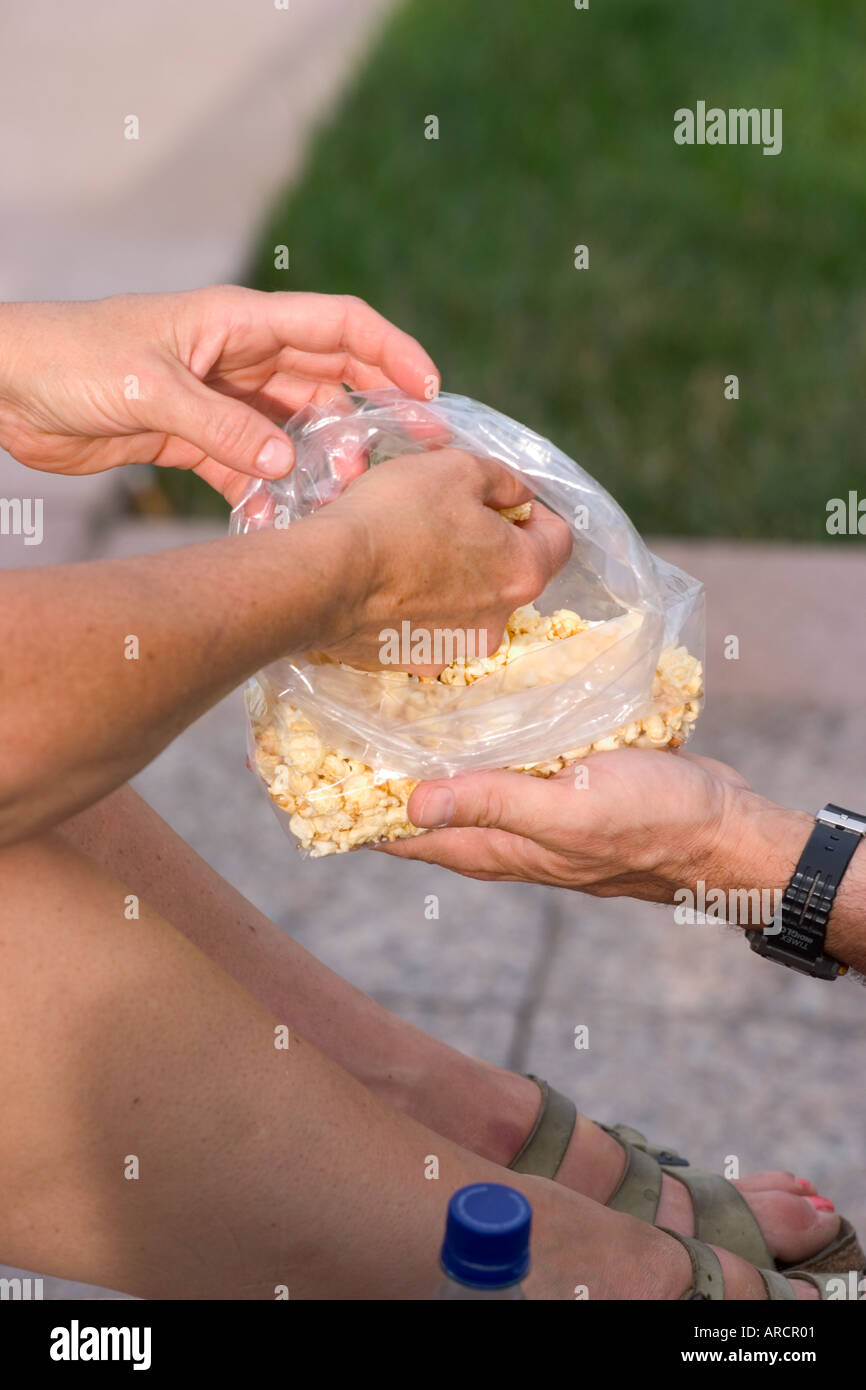 Man s hand offering popcorn from a plastic bag to another set of hands ...