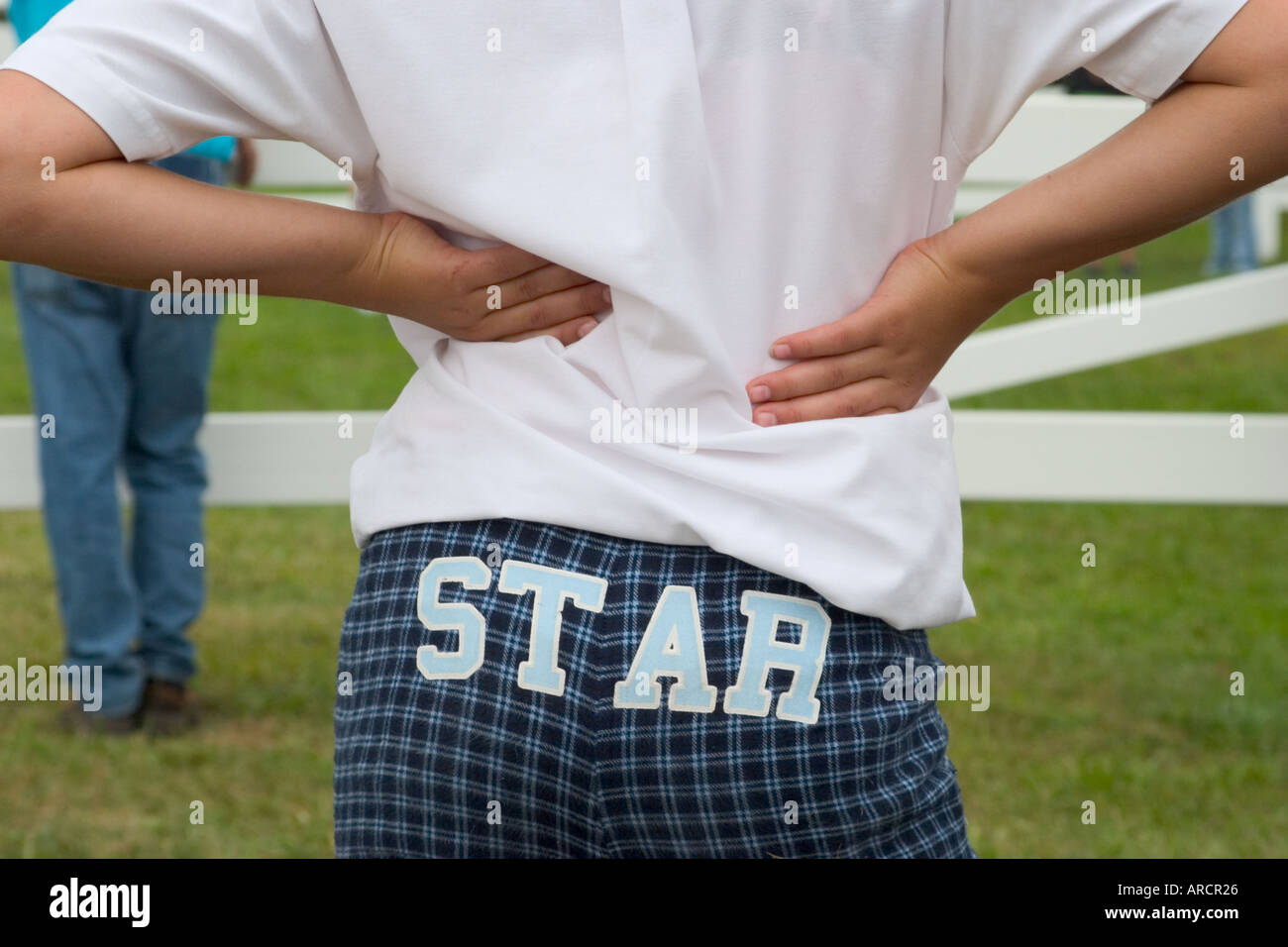 The backside of a preteen girl with her hands on her hips and the word ...