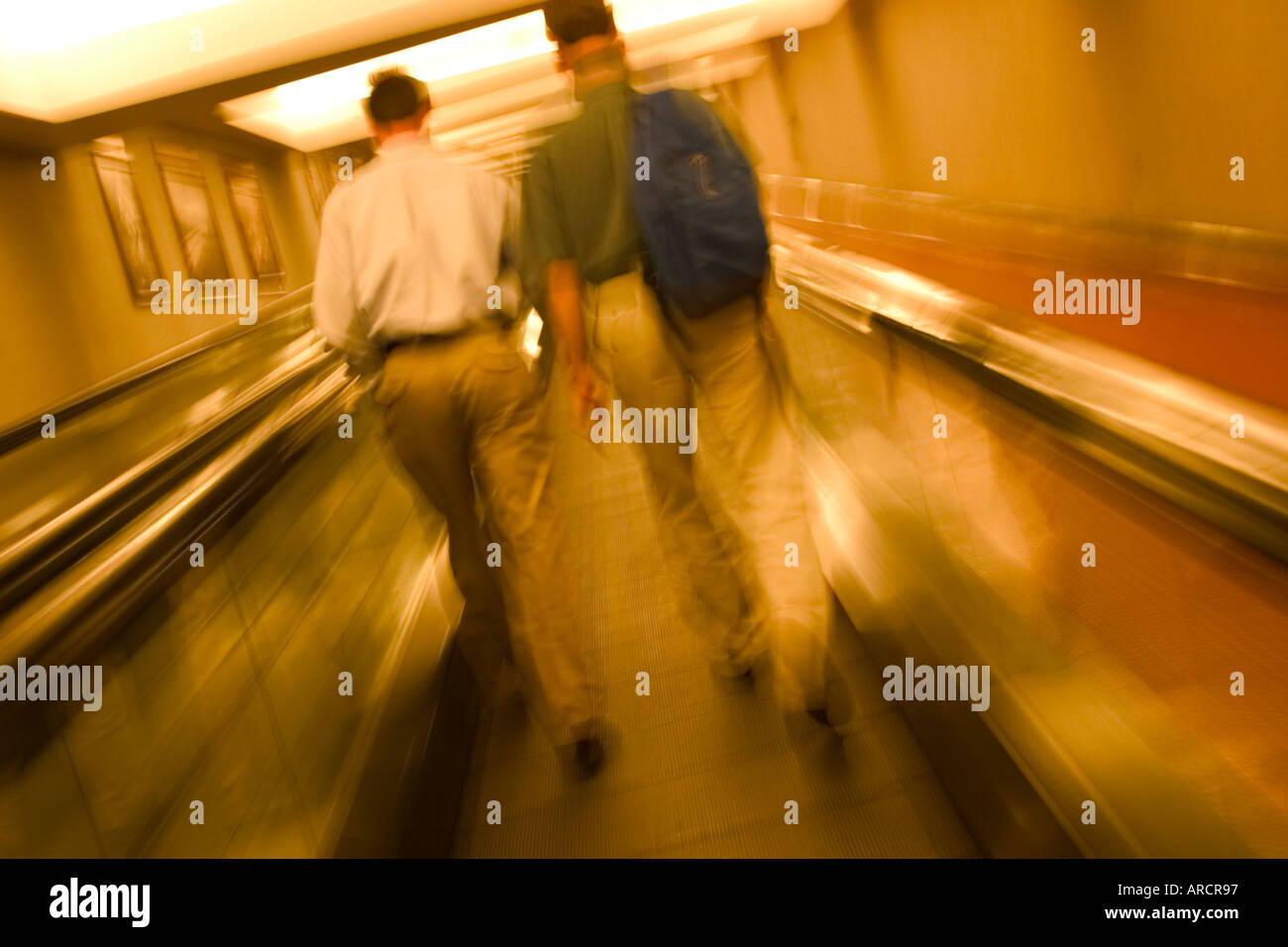 Two men on a moving walkway in an office building Stock Photo - Alamy