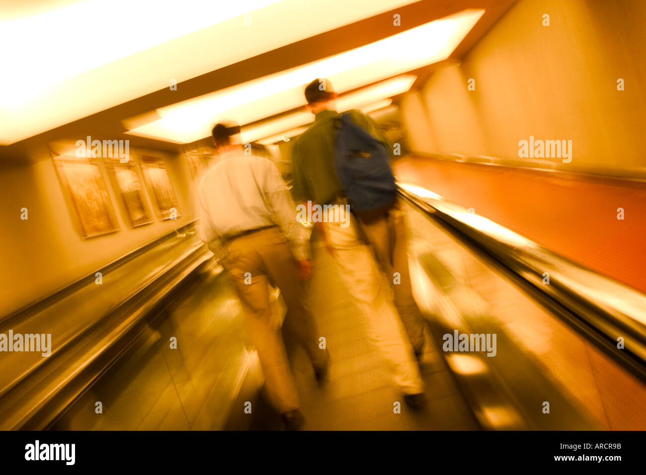Two men on a moving walkway in an office building Stock Photo - Alamy