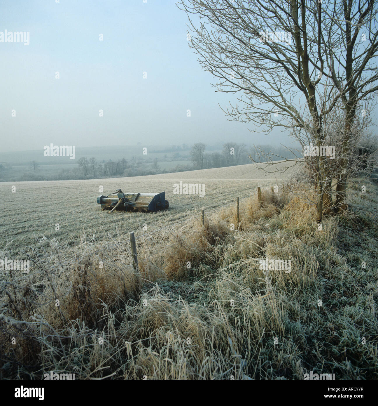 Hard frost covering on farmland with hedges fields and farm machinery ...