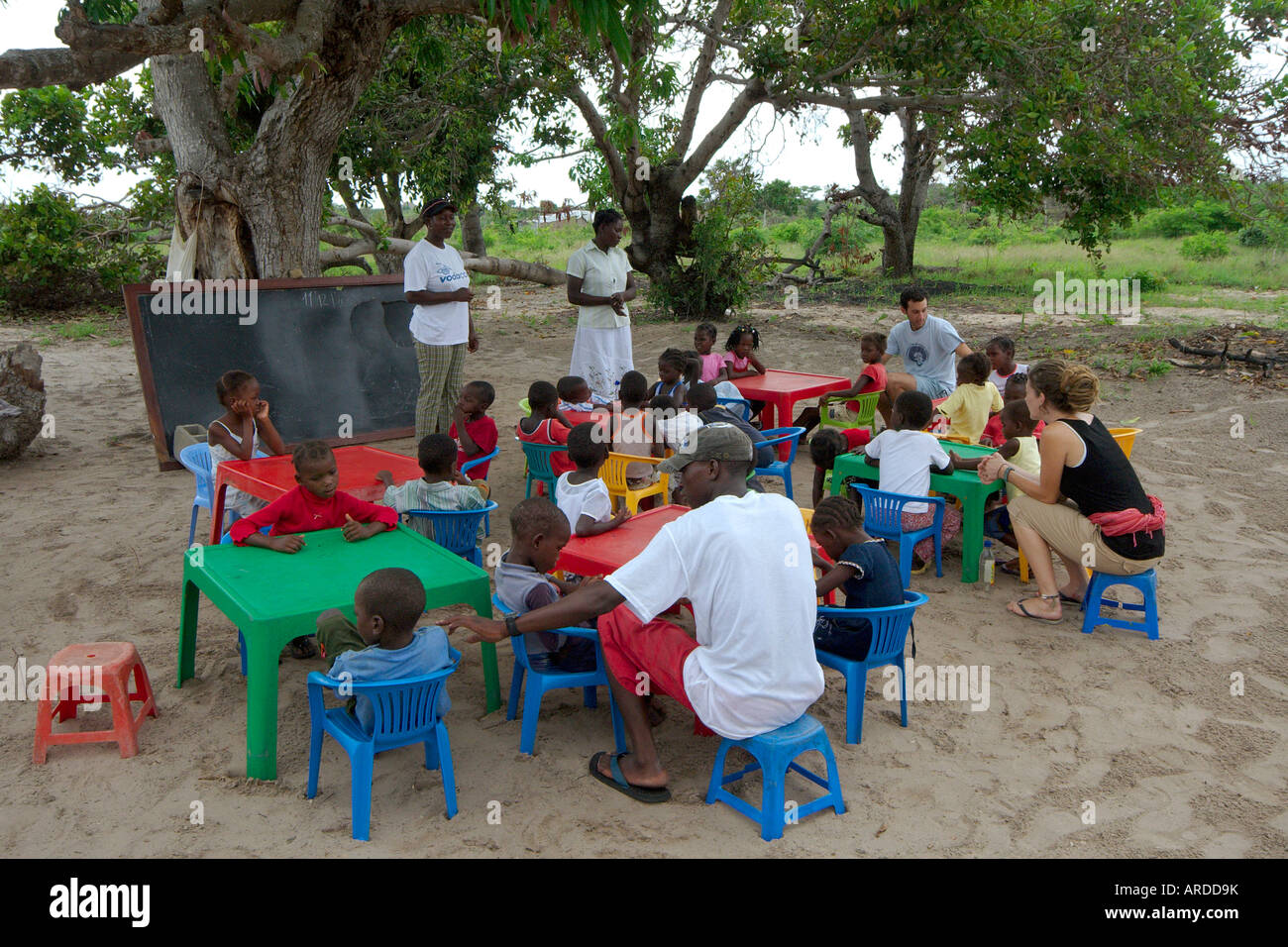 Volunteer teachers educate a class of Mozambican children in a bush ...
