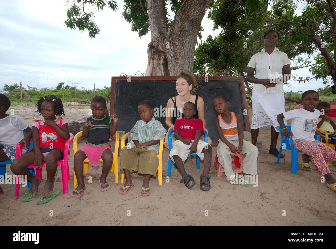 Volunteer teachers educate a class of Mozambican children in a bush ...
