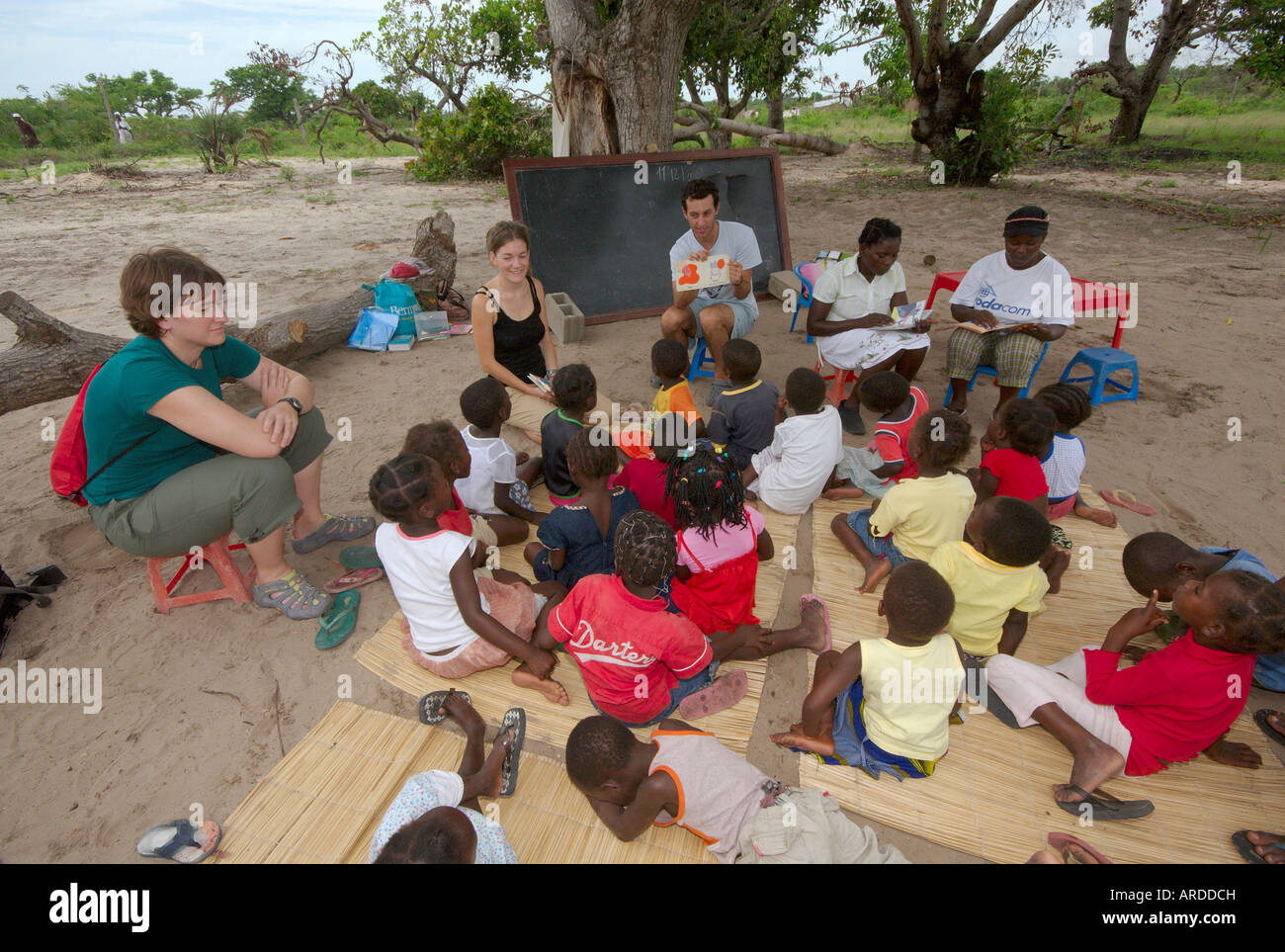 Volunteer teachers educate a class of Mozambican children in a bush ...