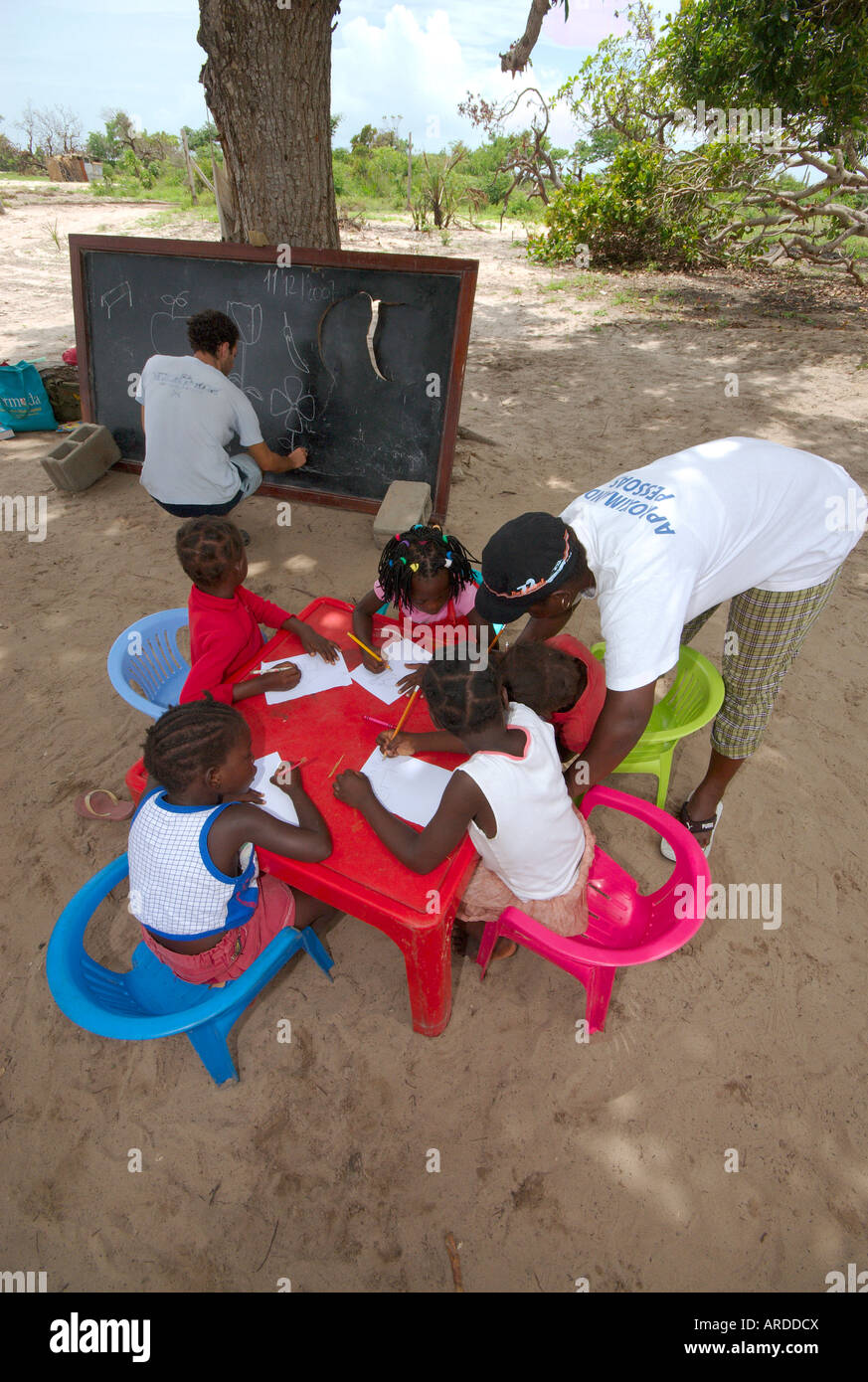 Volunteer teachers educate a class of Mozambican children in a bush ...