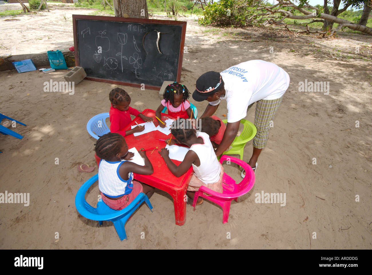 Volunteer teachers educate a class of Mozambican children in a bush ...