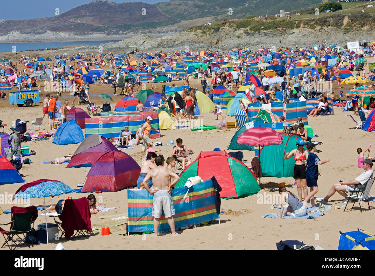 Holidaymakers with tents umbrellas and windbreaks on crowded sandy ...