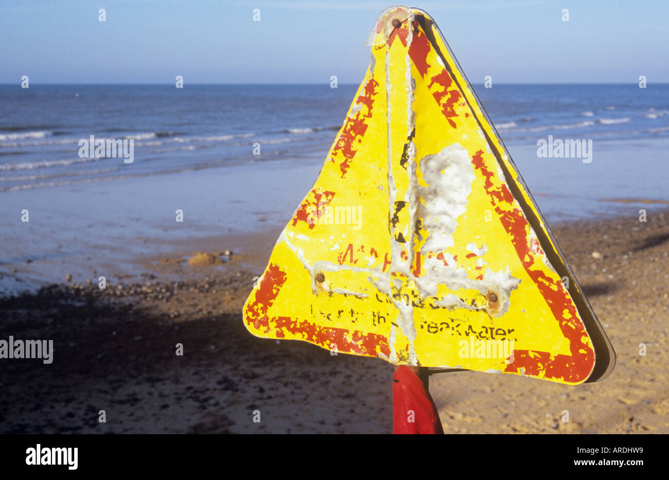 Illegibly battered triangular red and yellow sign warning of ...