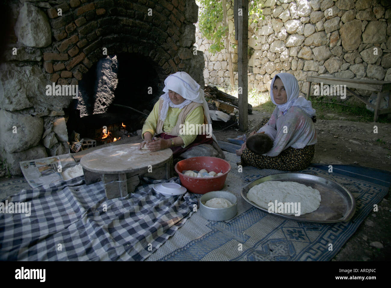 Old turkish women bake pitta bread in traditional wood fire oven one ...