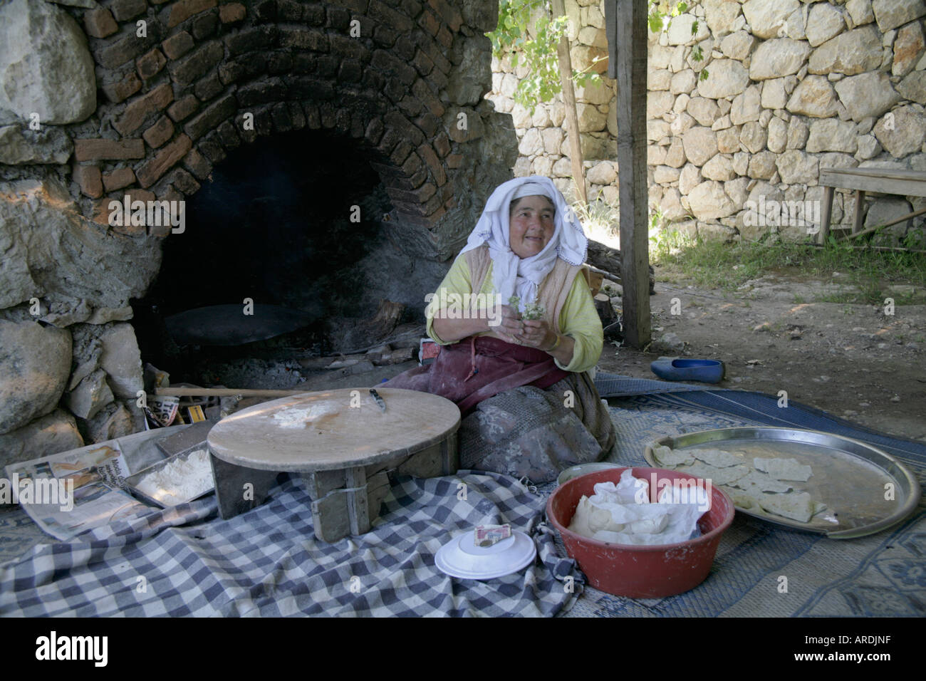 Old turkish woman bakes pitta bread in traditional fire oven holding ...