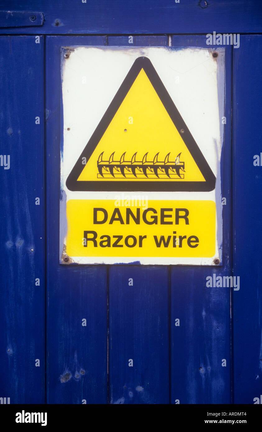 Graphic yellow and black sign with words Danger Razor wire attached to ...