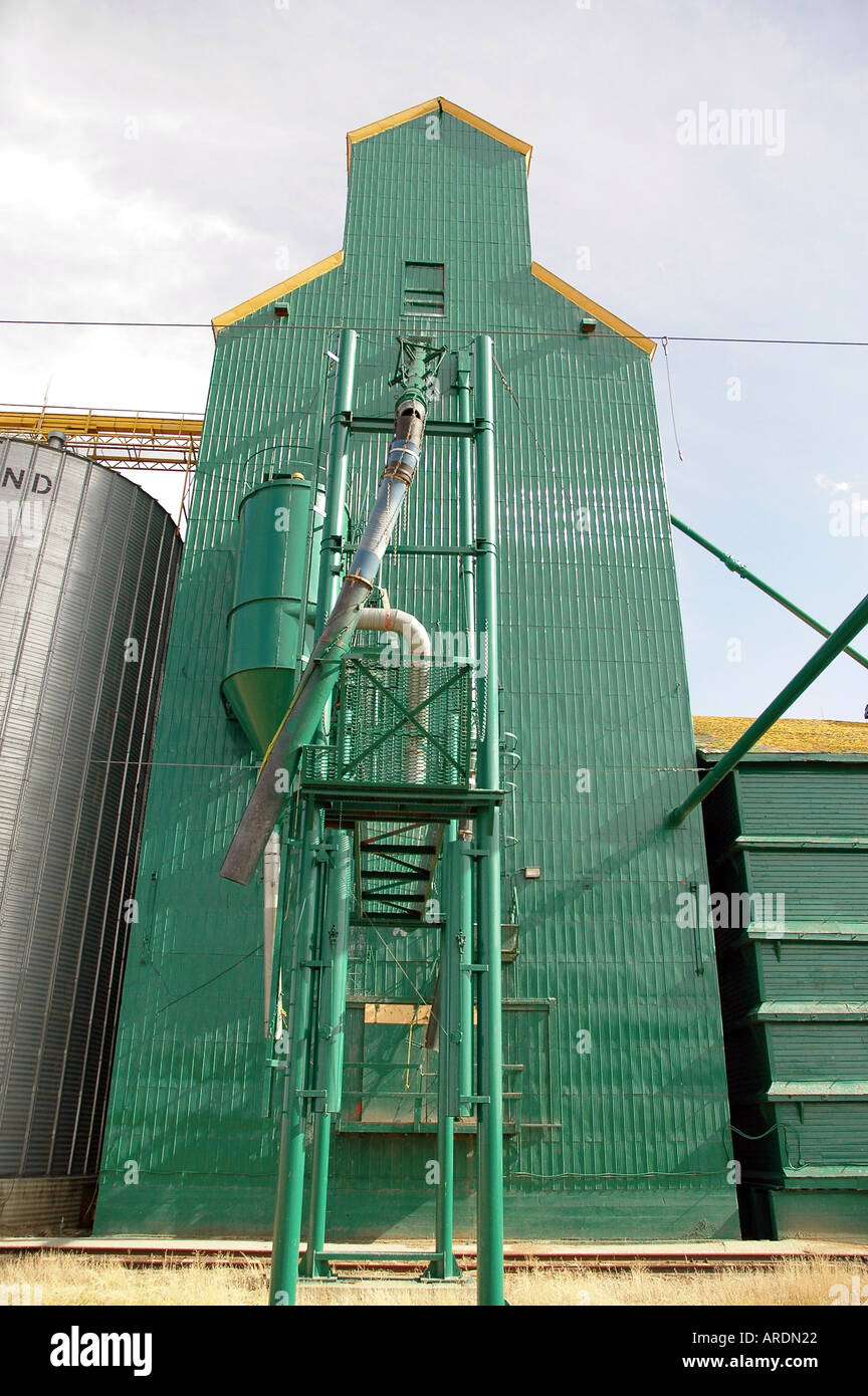 A green grain elevator towers over railroad tracks and the grassy ...