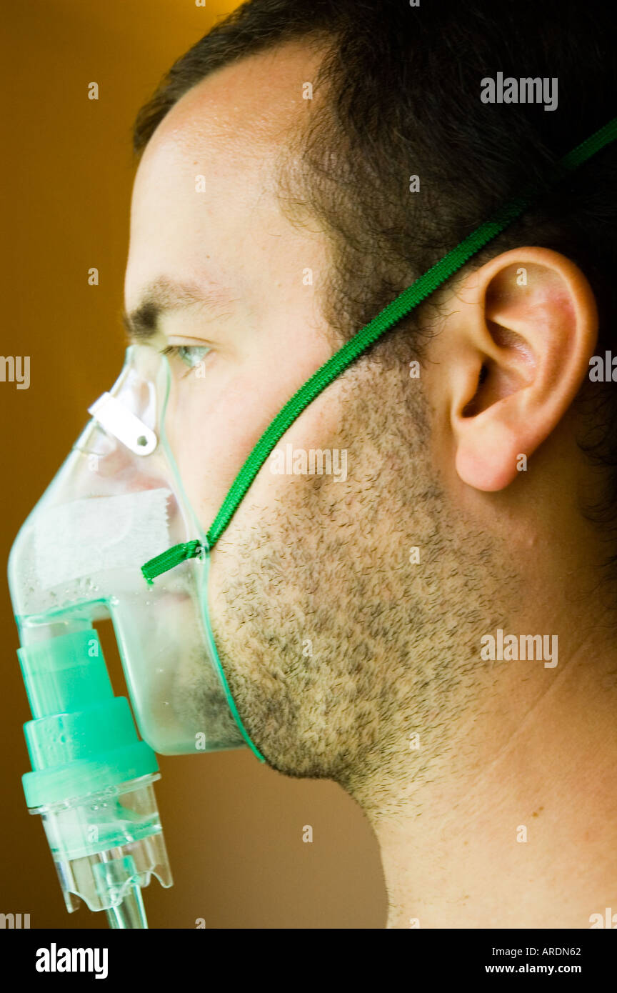 A patient wears an oxygen mask to receive treatment for a respiratory ...