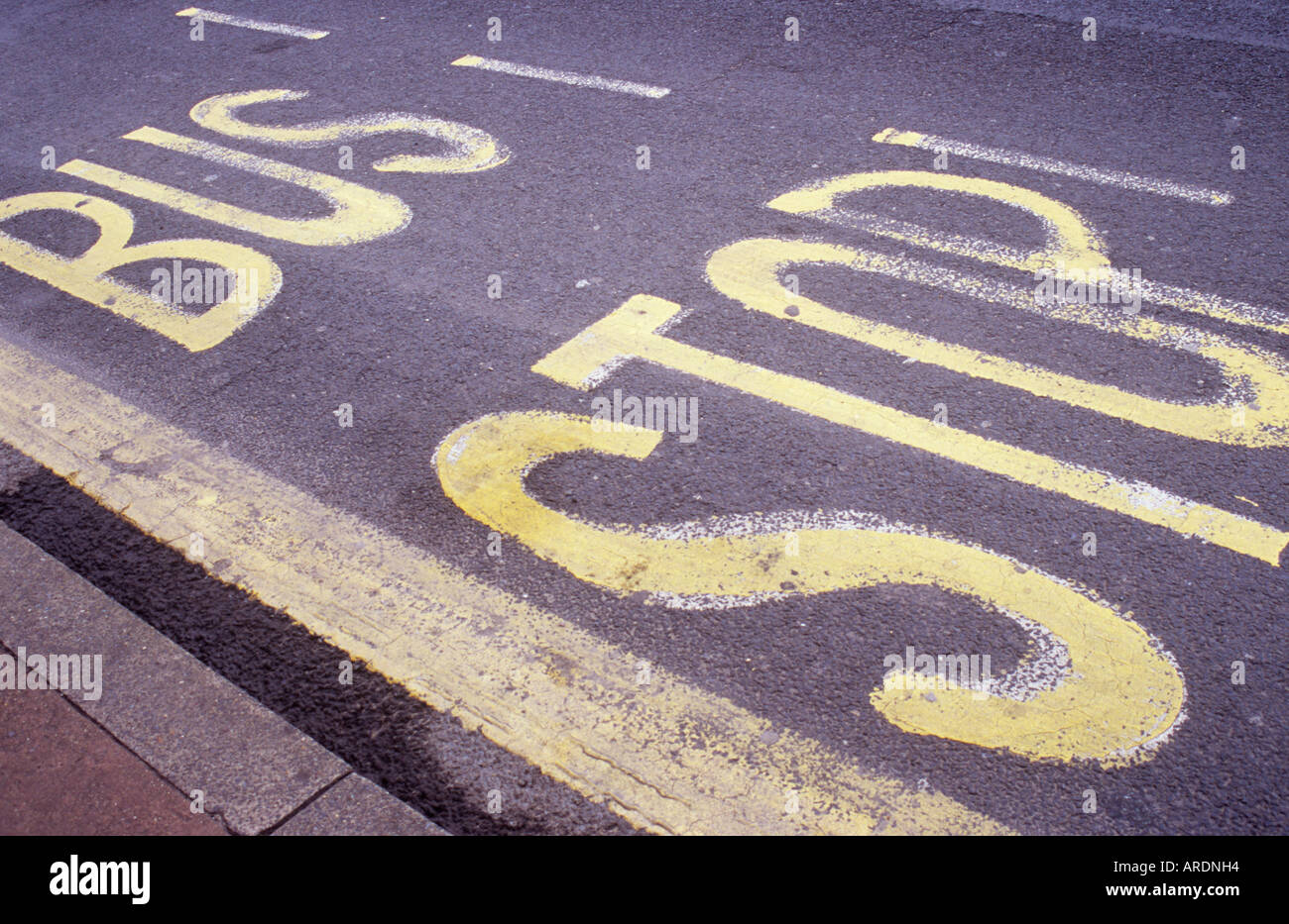 Angled view from pavement and kerb of well worn letters and lines ...