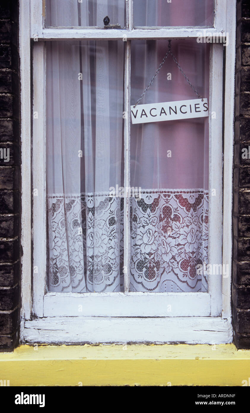 Close up of narrow sash window with flaking paint and grimy brickwork ...