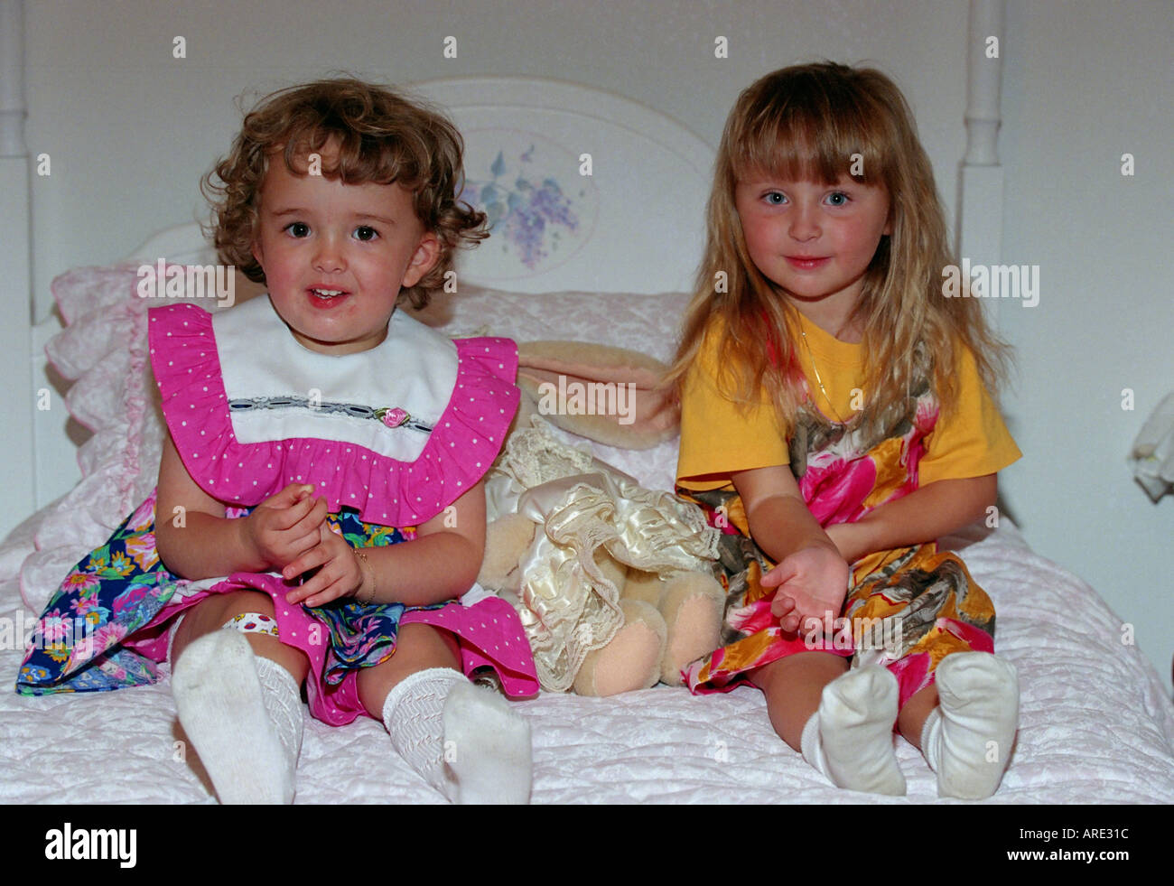 Two young female cousins sitting on bed Stock Photo - Alamy