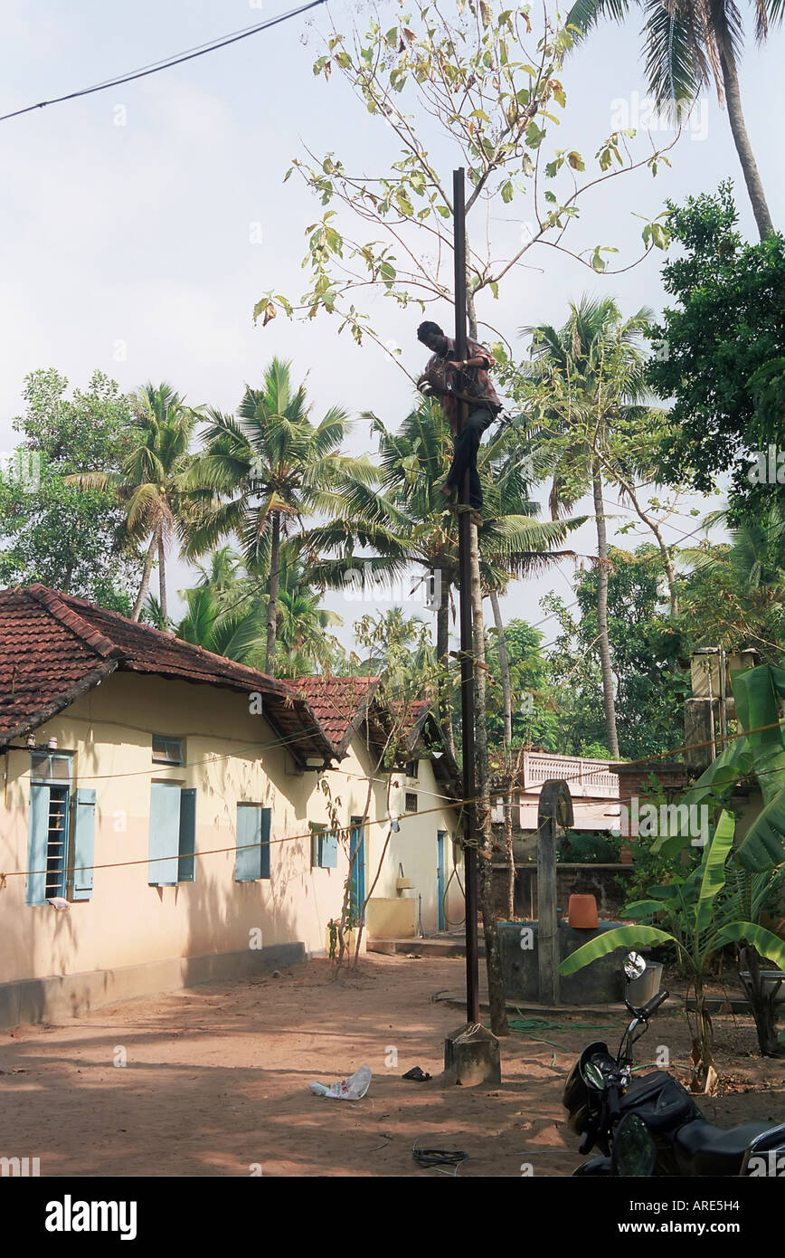 local electrician fixing the electric line on a makeshift pole India ...