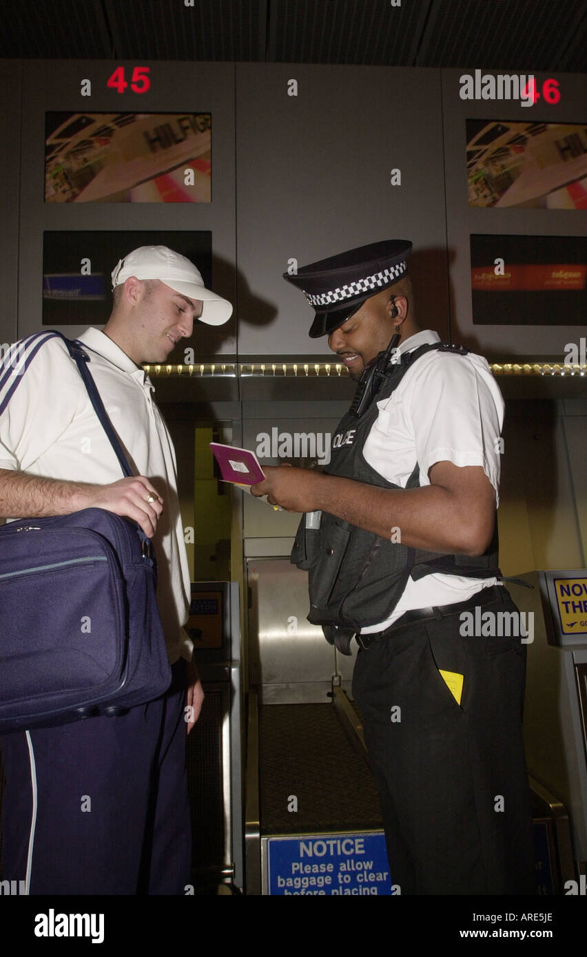 Police officer checks the details of a traveller at London Luton ...