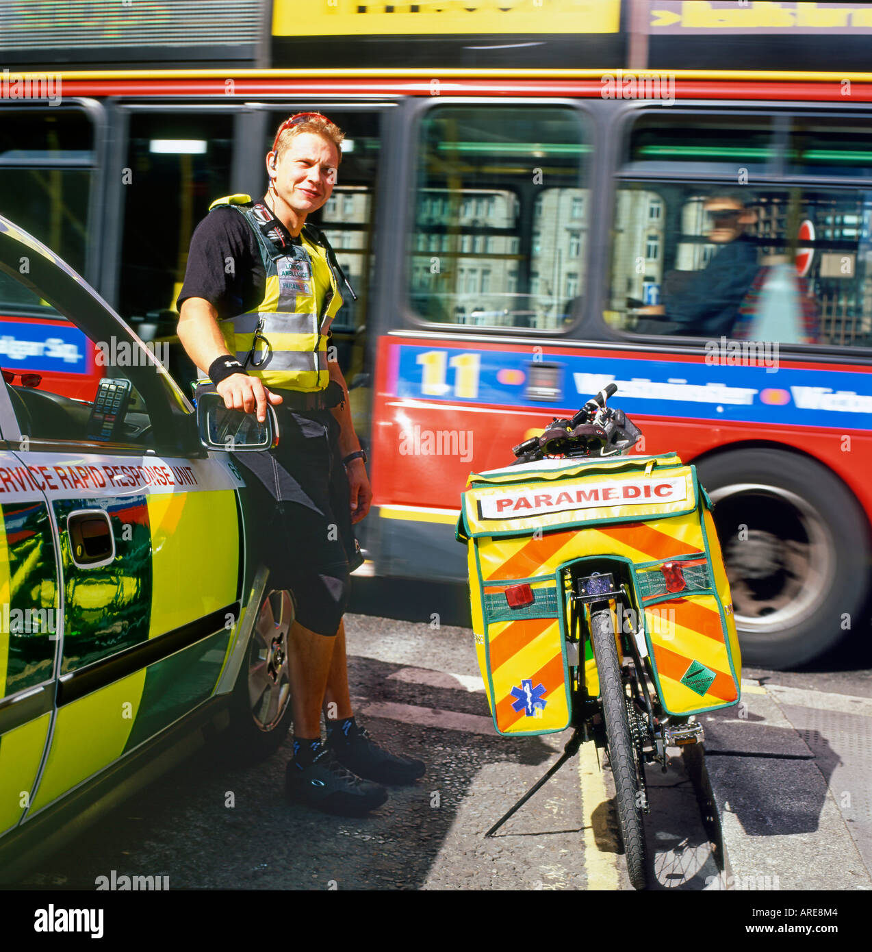 Paramedic from the London Ambulance Service standing by car and bike as ...