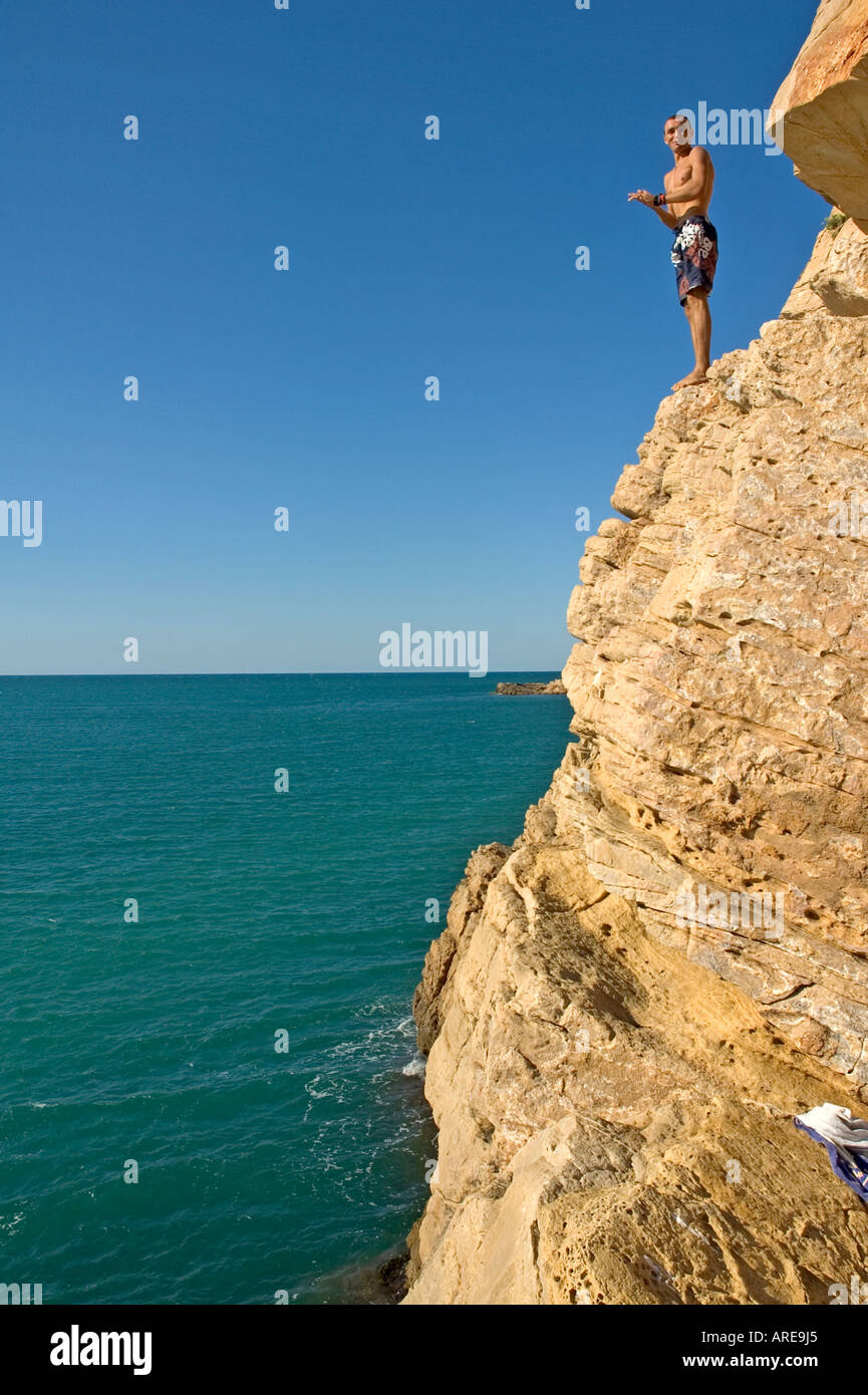 A local teenager standing at the top of a big rock, ready to dive into ...
