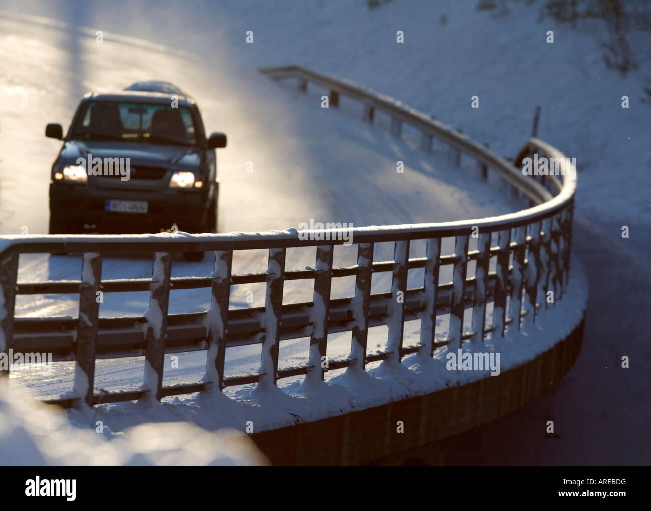 Metallic snowy road bridge railing and car driving on the road at ...