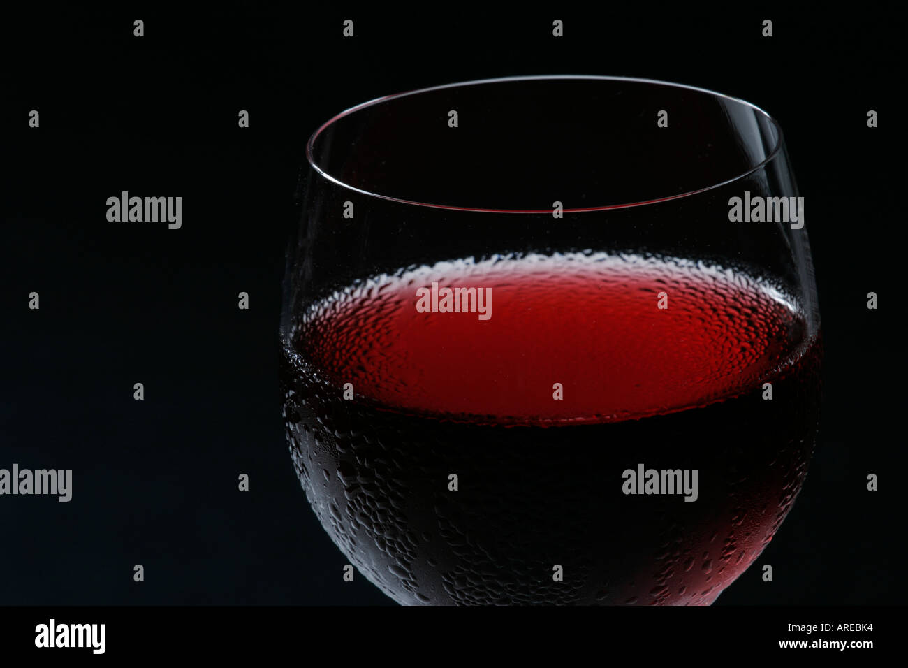 Close up of a glass of chilled rose wine against a black background ...
