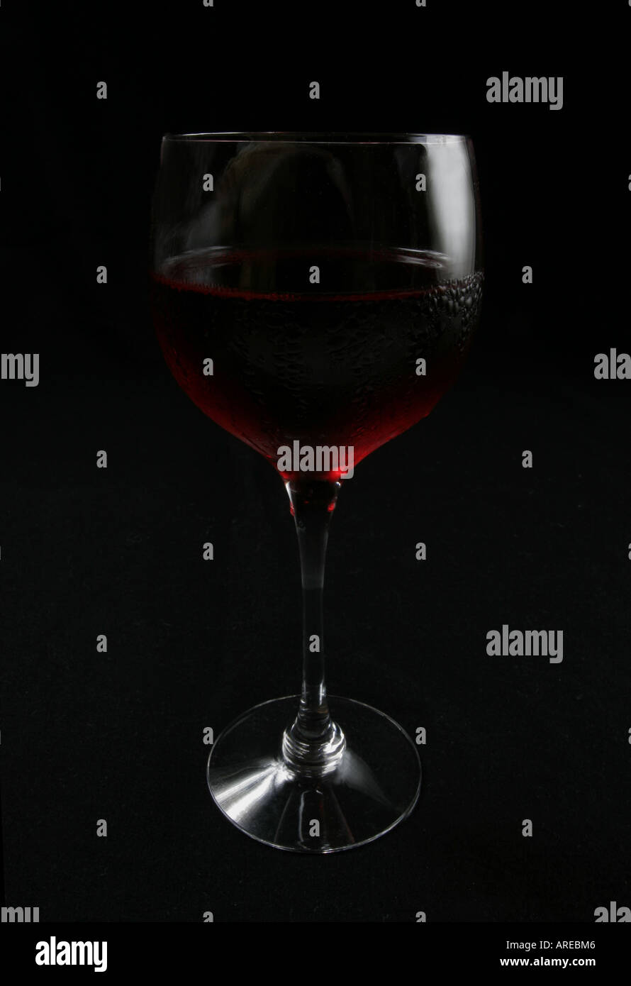 Wide angle close up view of a glass of red wine against a black ...
