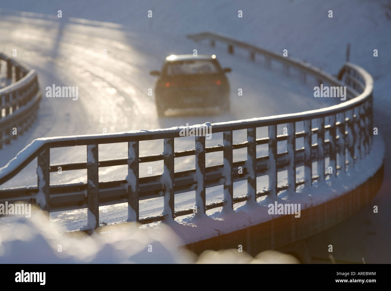 Metallic snowy road bridge railing and car driving on the road at ...