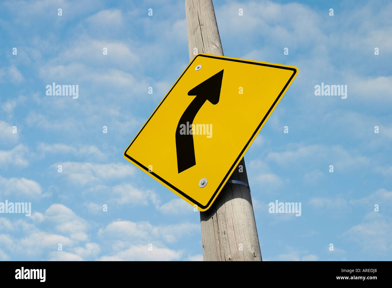 A black and yellow diamond shaped slight bend or curve right ahead road ...