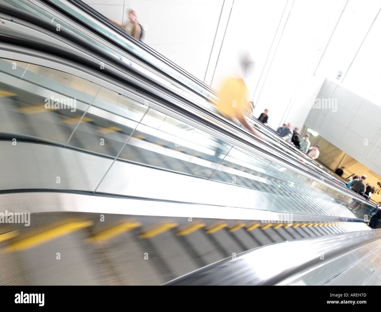 Airport patrons ride the escalators between the terminal gates and ...
