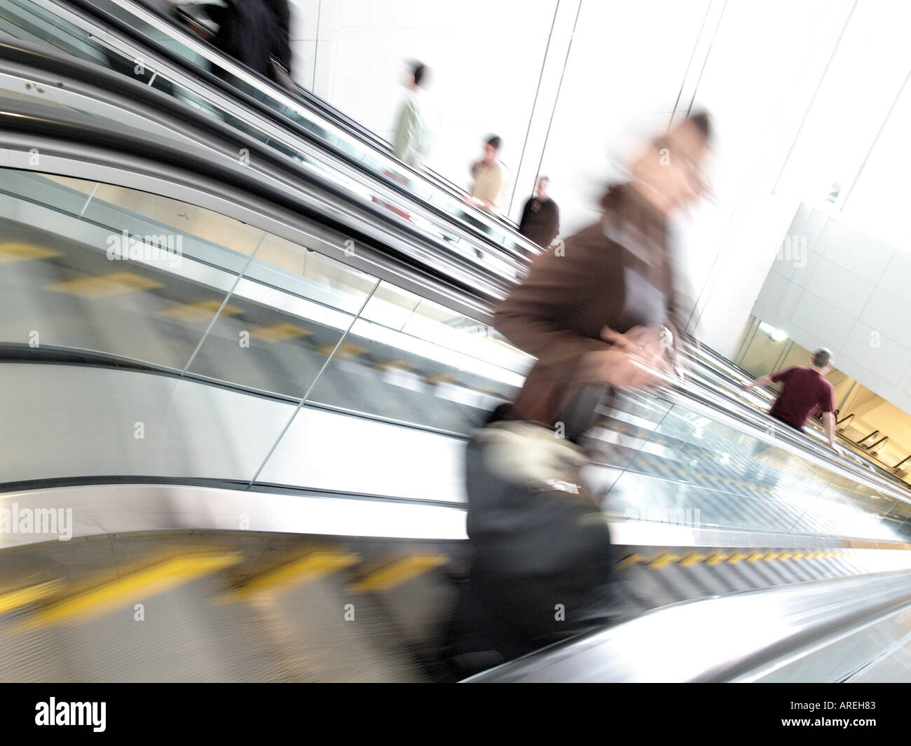 Airport patrons ride the escalators between the terminal gates and ...