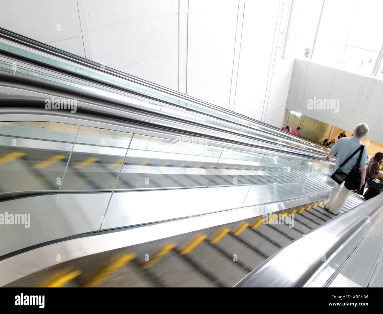 Airport patrons ride the escalators between the terminal gates and ...