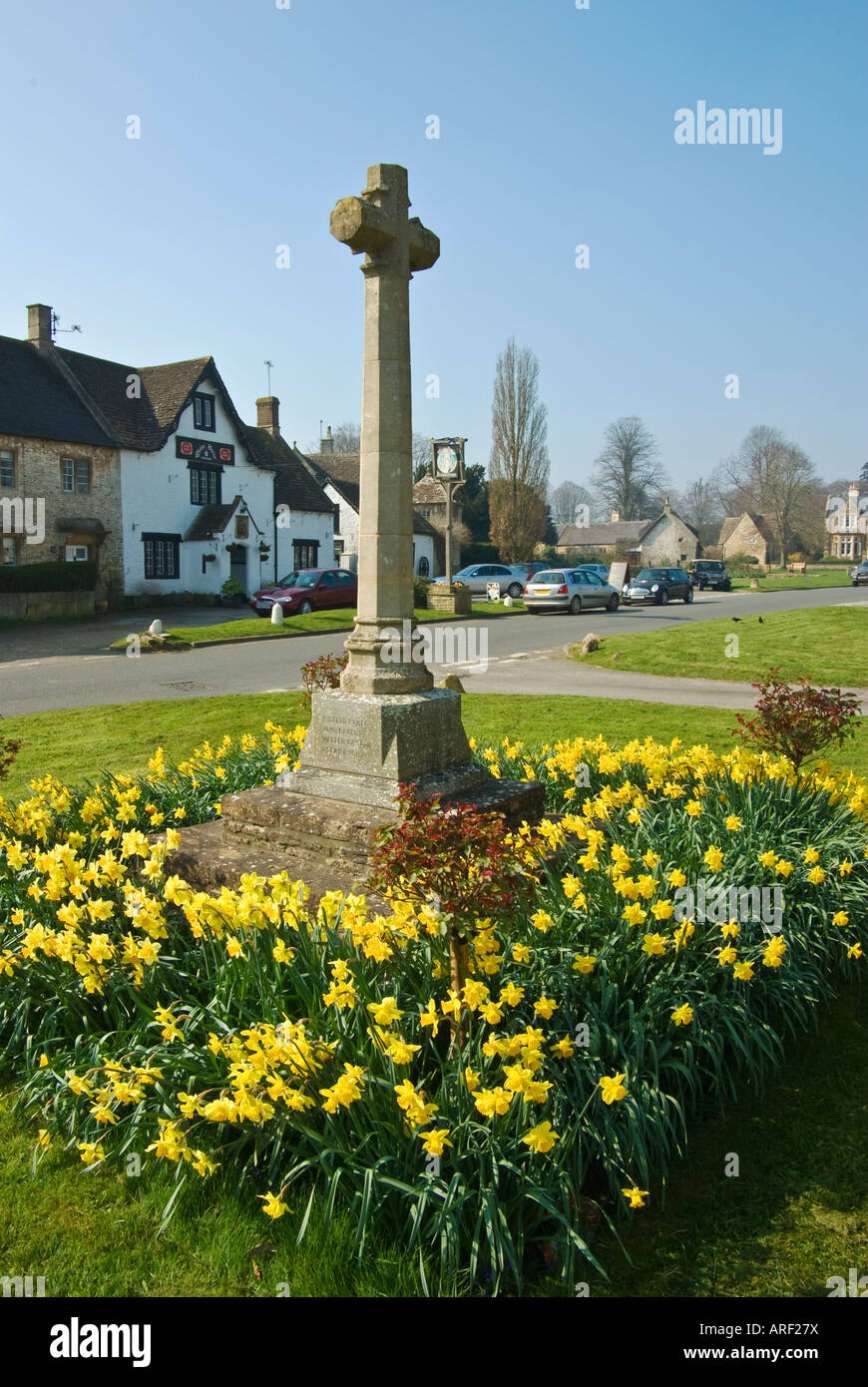 Memorial cross and daffodils on the green in Biddestone village in ...