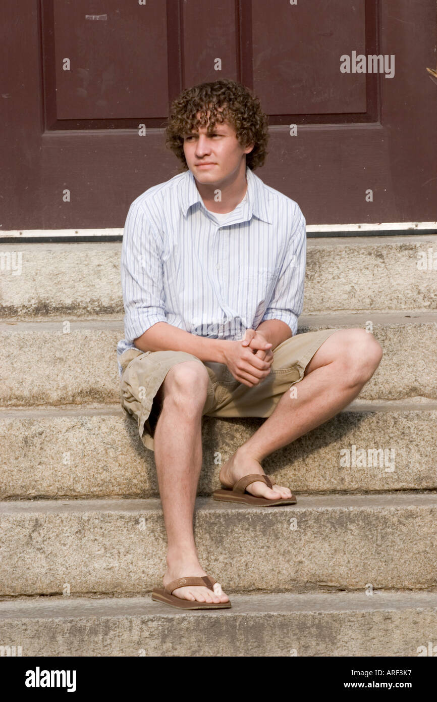Young man sitting on steps of building outdoors Stock Photo - Alamy