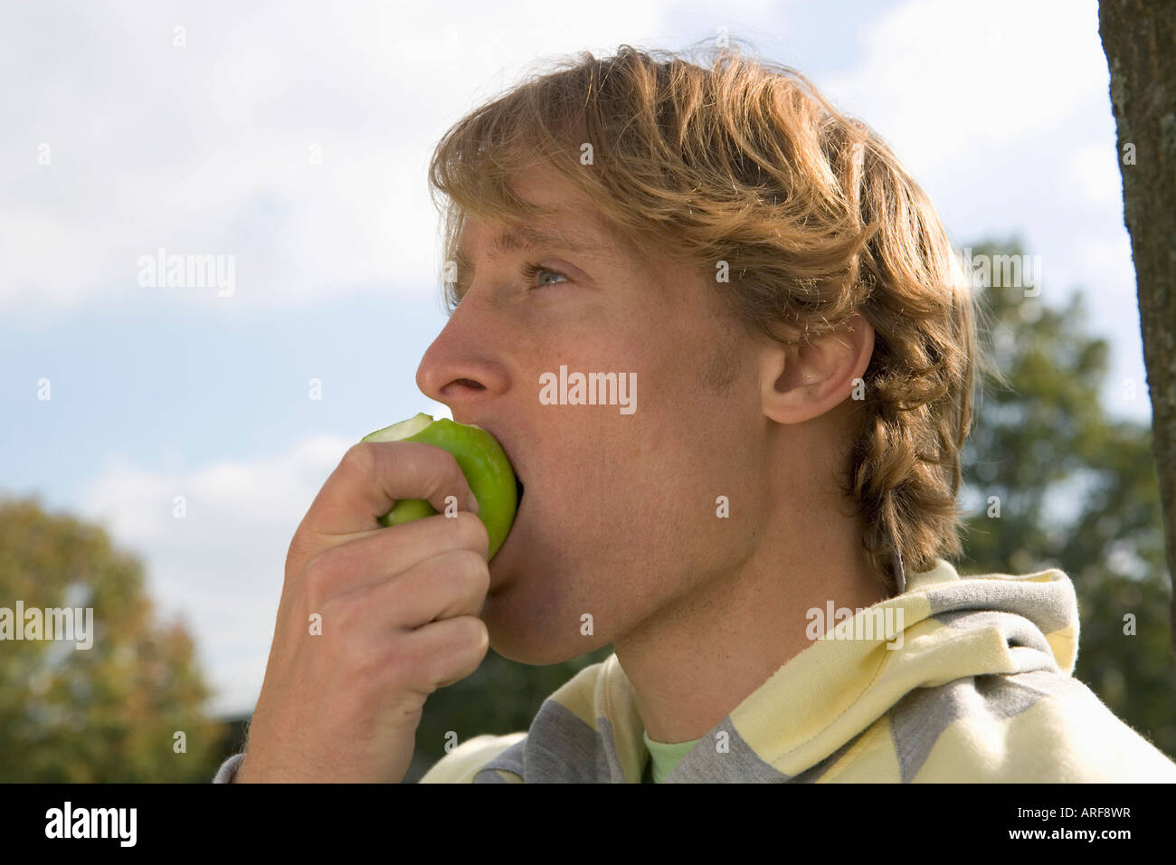 Young man eating apple Stock Photo - Alamy