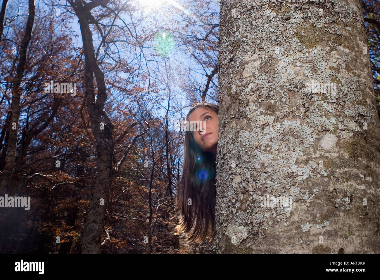 Young woman hiding behind a tree Stock Photo - Alamy