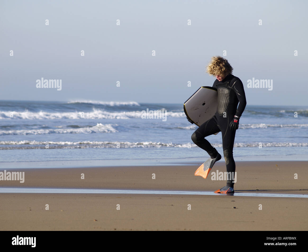 Bodyboarder walking along the beach with flippers on his feet Stock ...