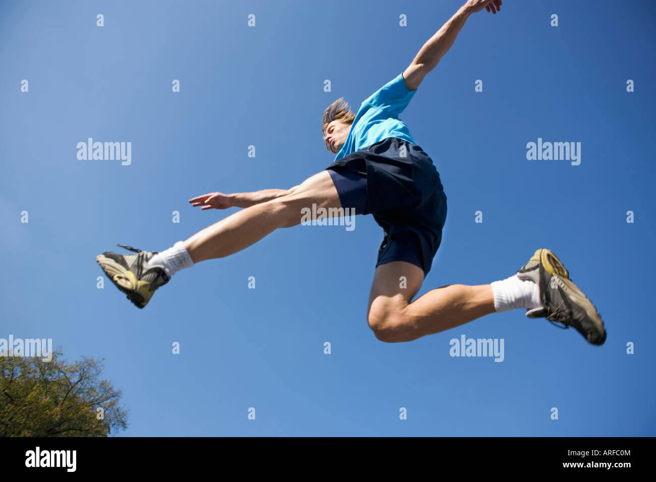 Young man jumping in sports kit Stock Photo - Alamy