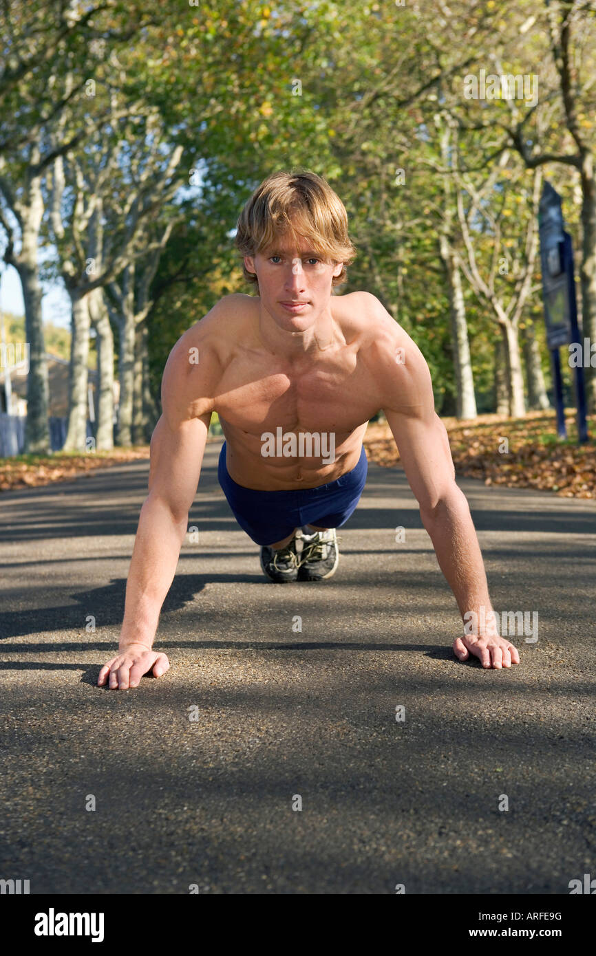 Young man doing push-ups in park Stock Photo - Alamy