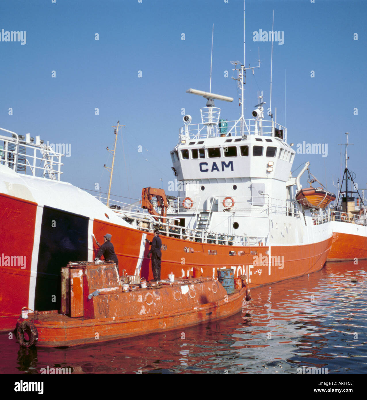 Men painting the hull of an oil rig support vessel, ship repair yard ...