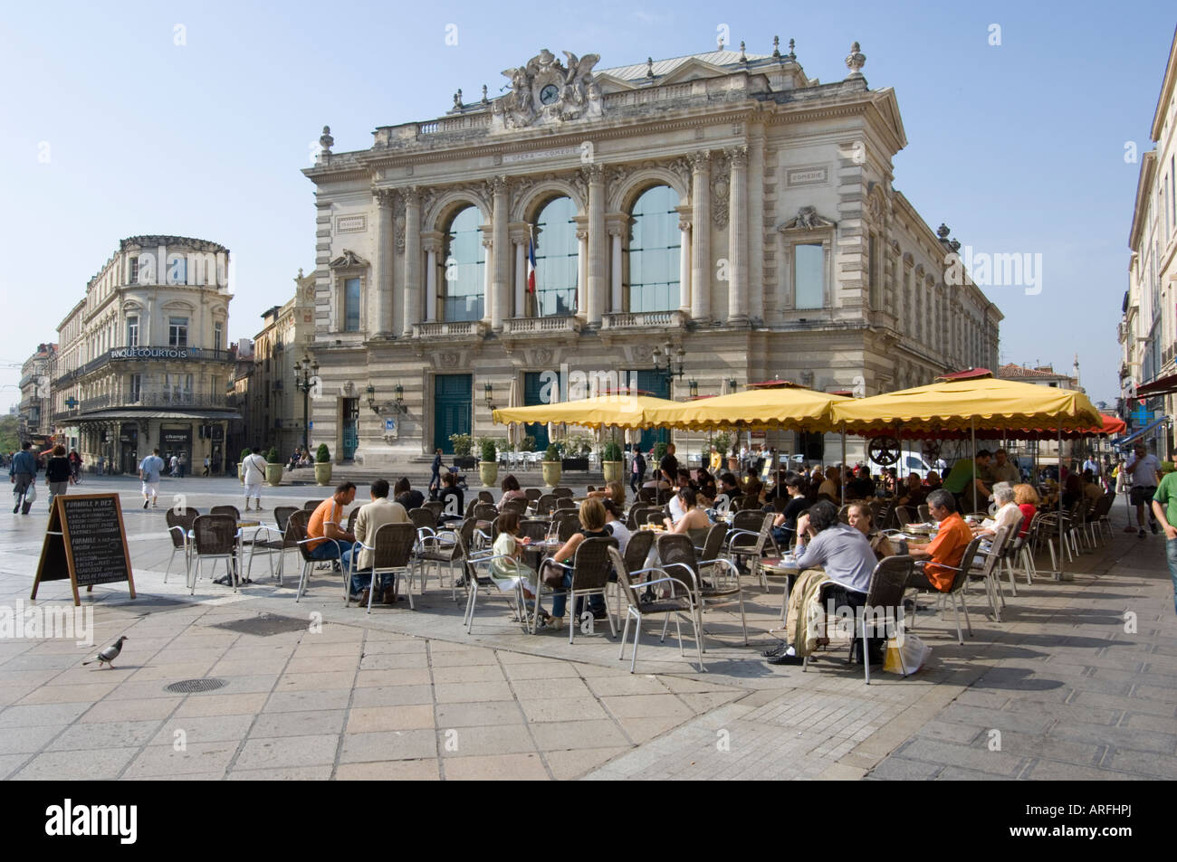 people sitting at outdoor cafe terrace in front of theater opera house ...