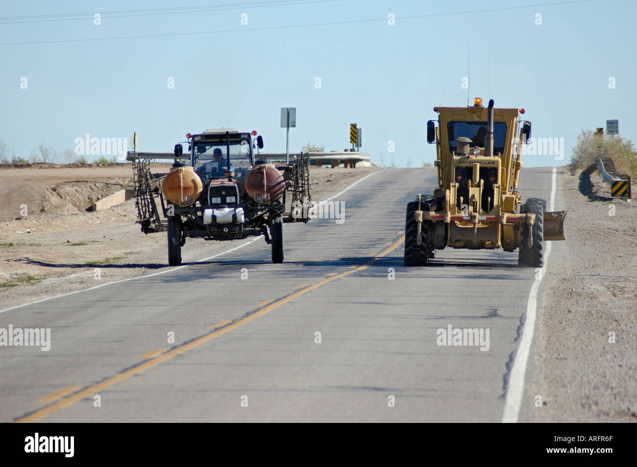 Working farm tractors passing on real farm road in rural Arizona in ...