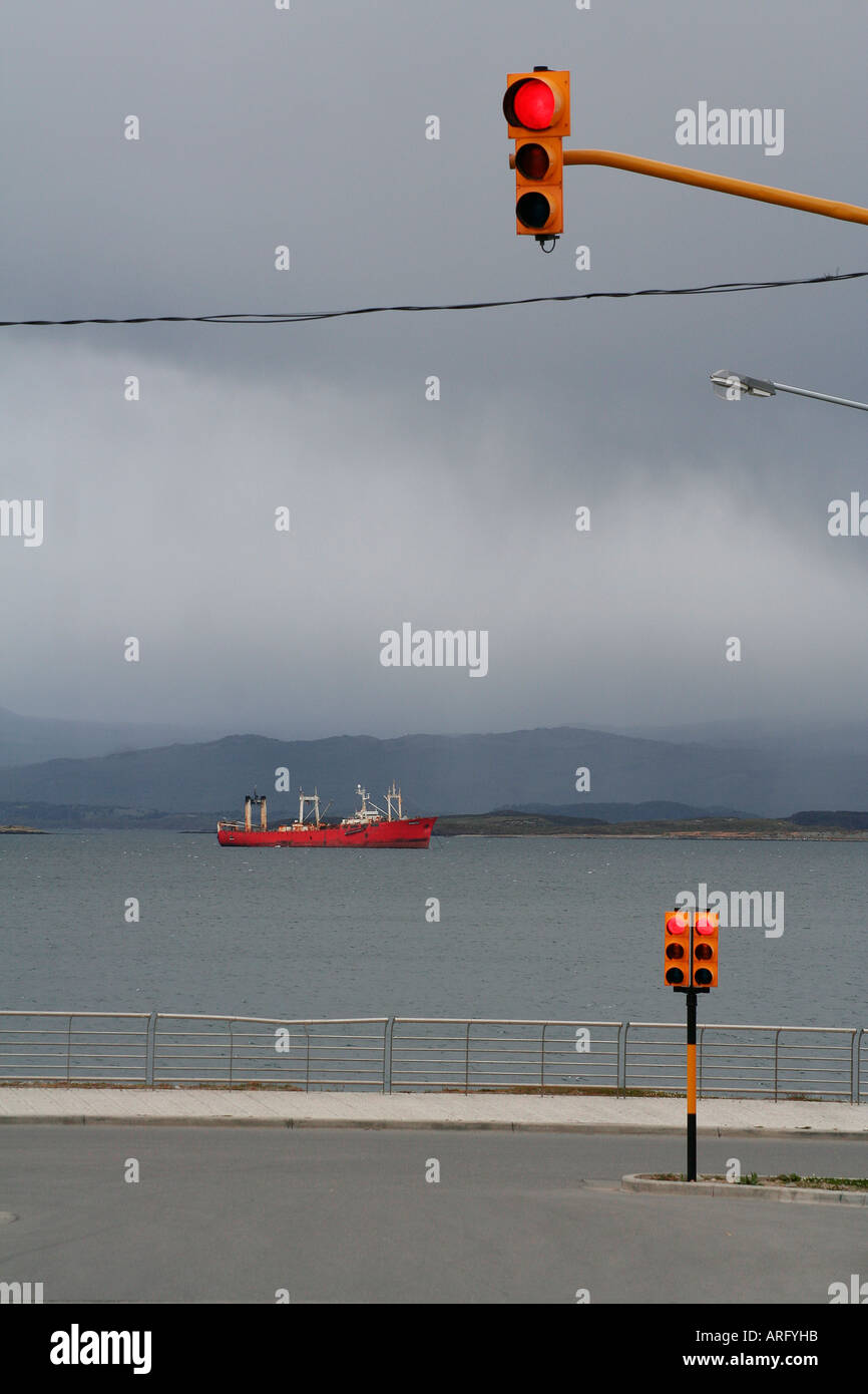 Red traffic lights overlooking red boat within grey landscape on the ...