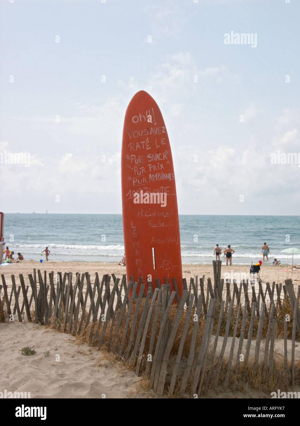 an orange surfboard being used as a menu on a beach in carnon, southern ...