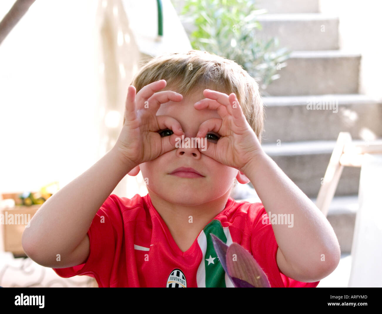 a small boy looking through a fake set of glasses made by his hands ...