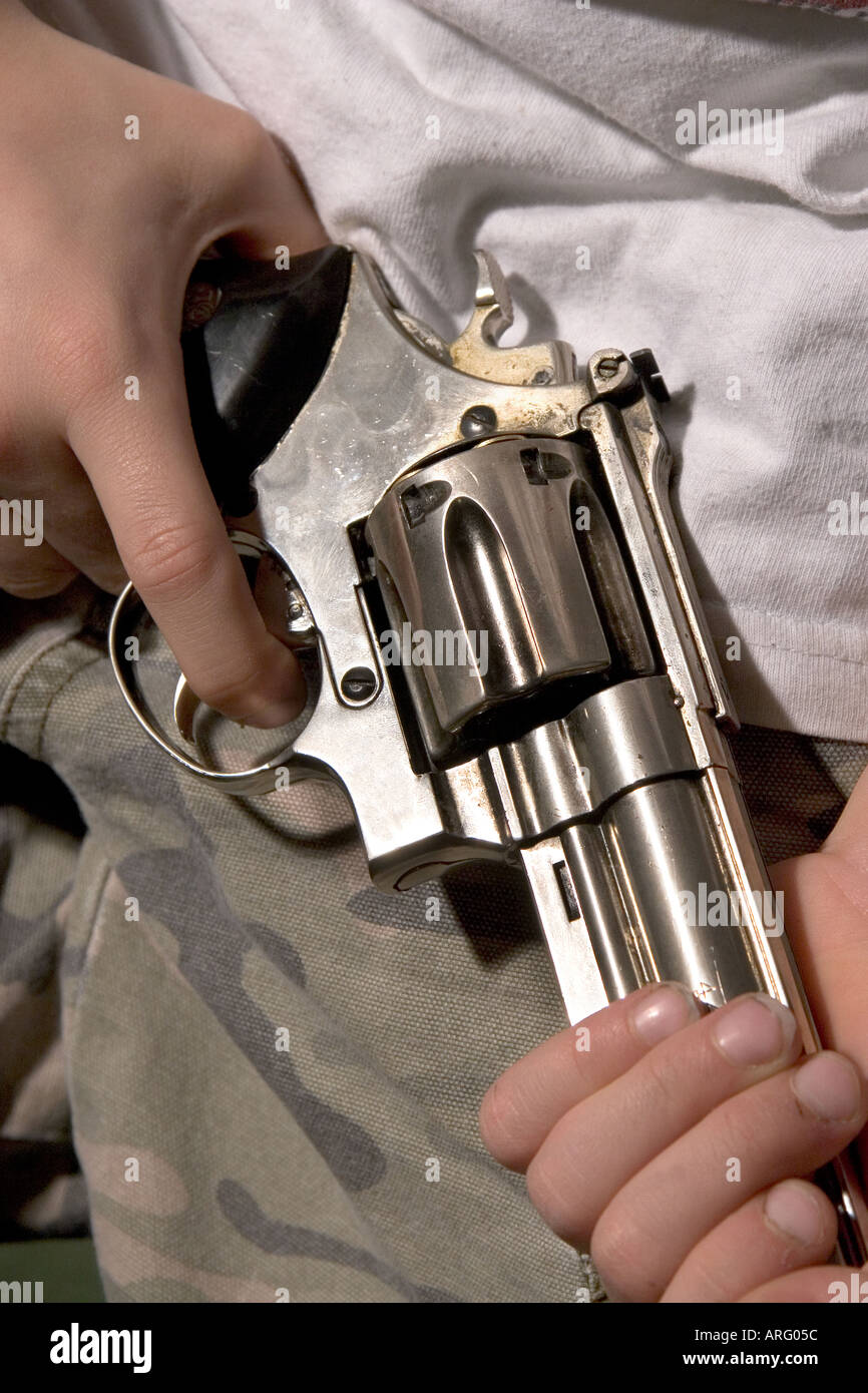 Close up of hand of young boy holding a gun with his finger on the ...