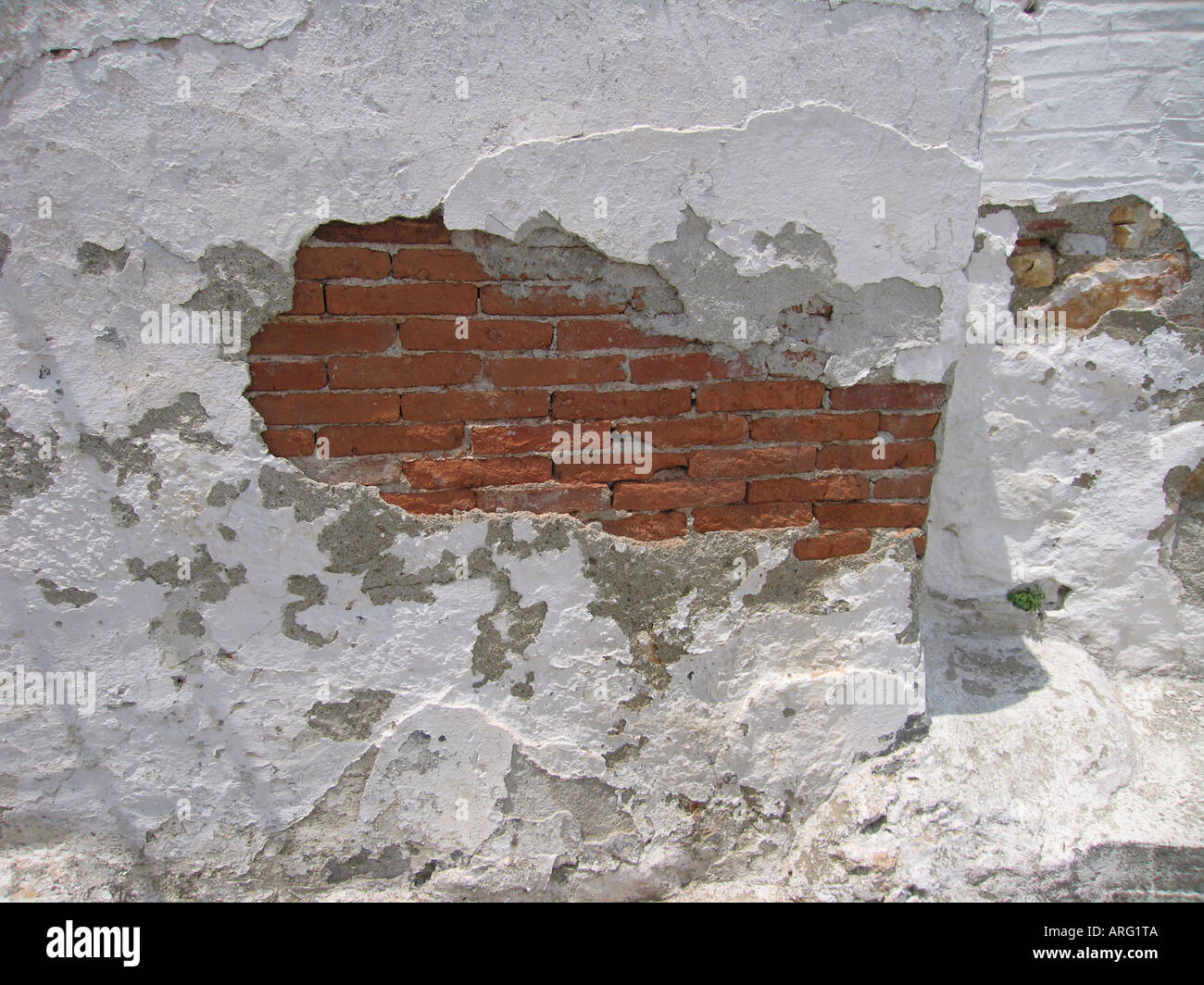 Damaged broken wall with bricks showing through Stock Photo - Alamy