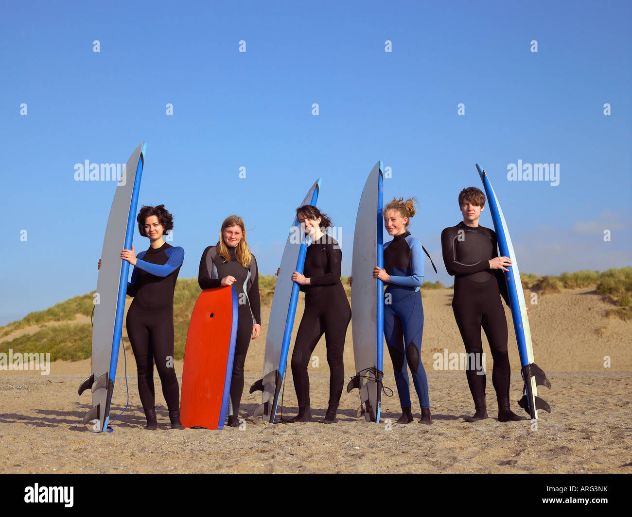 Five teenage surfers on a beach Stock Photo - Alamy